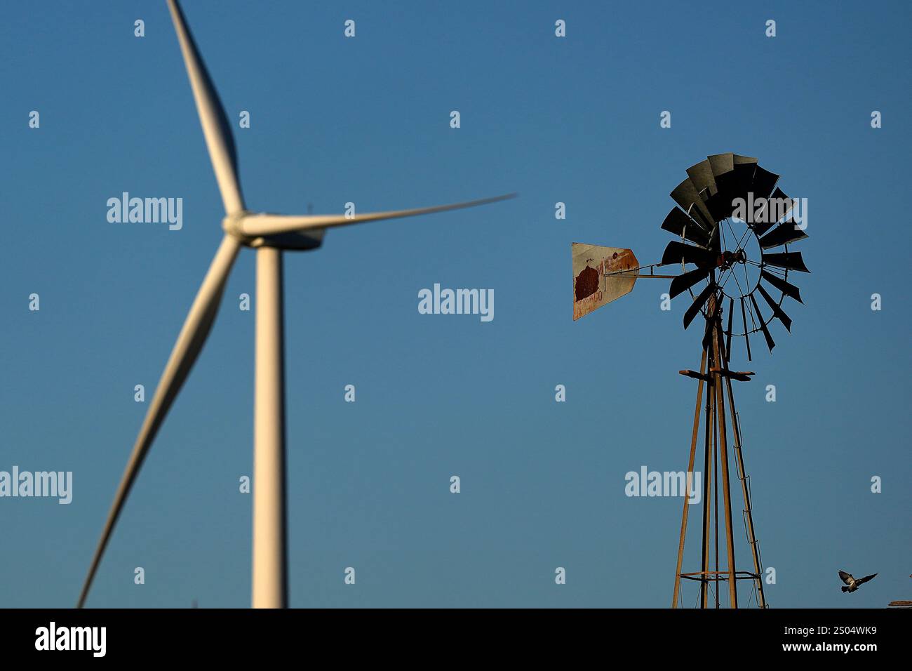A wind turbine stands in contrast to an old windmill at the Smoky Hills ...