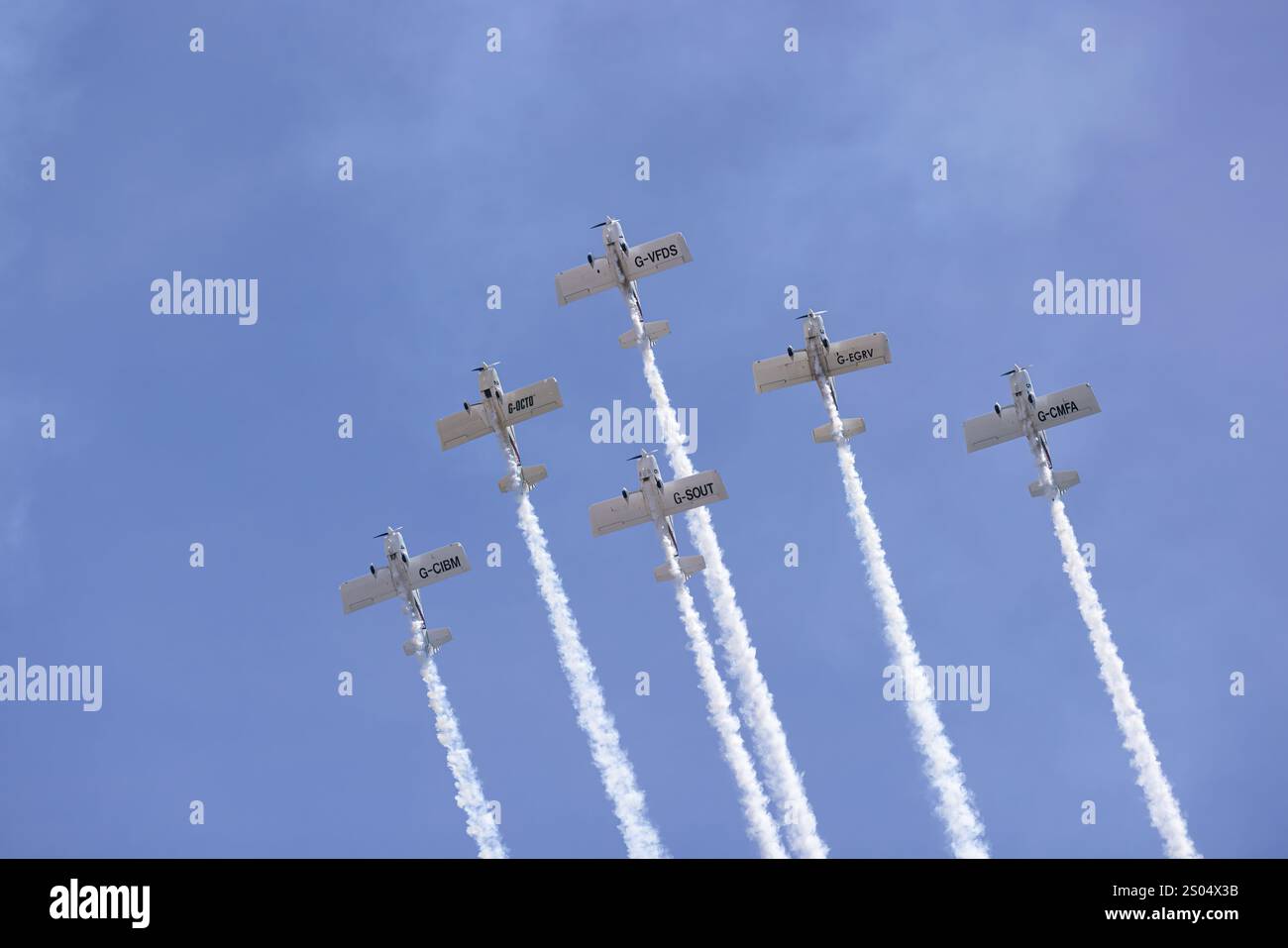 Six aerobatic planes perform a synchronized formation with smoke trails ...