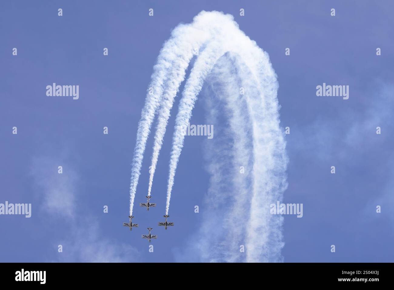 Aerobatic planes perform a precision maneuver, creating a smoke arc ...