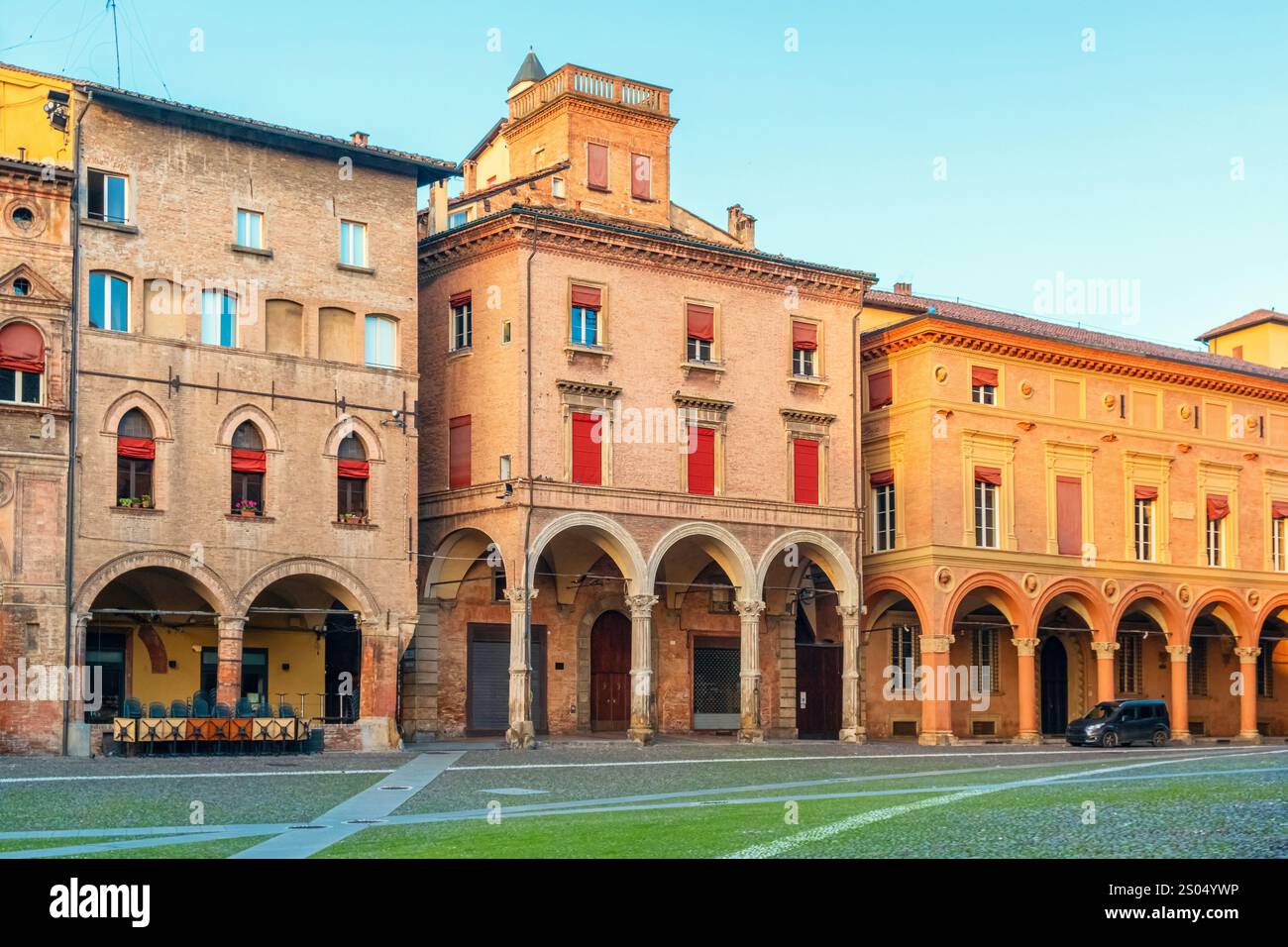 Facade of a historic buildings with arched porticoes, red shutters and ...