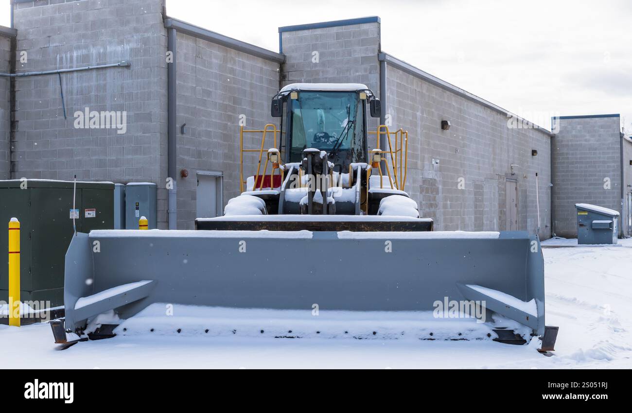 A John Deere wheel loader tractor with a snowplow on it parked next to ...
