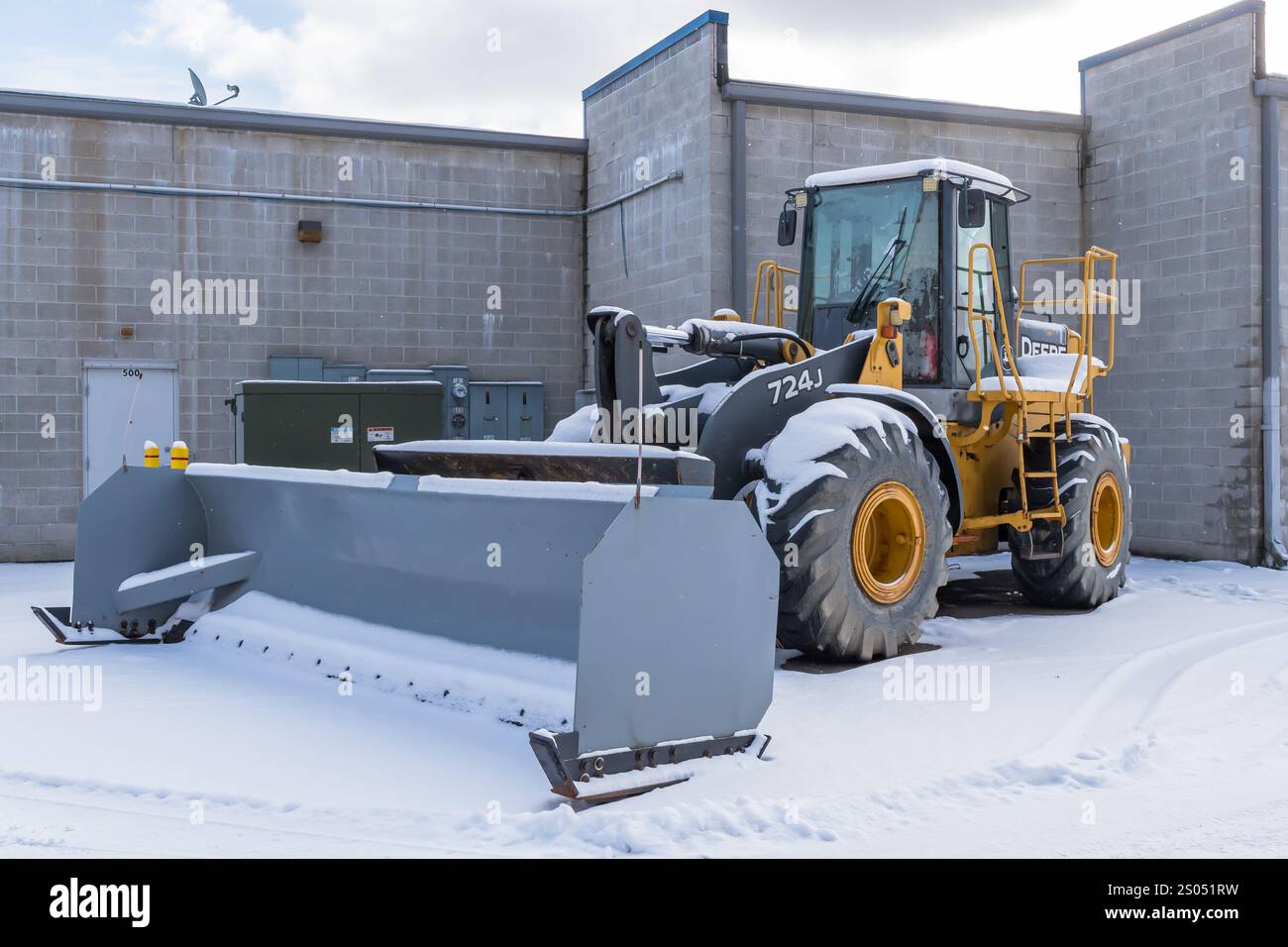 A John Deere wheel loader tractor with a snowplow on it parked next to ...