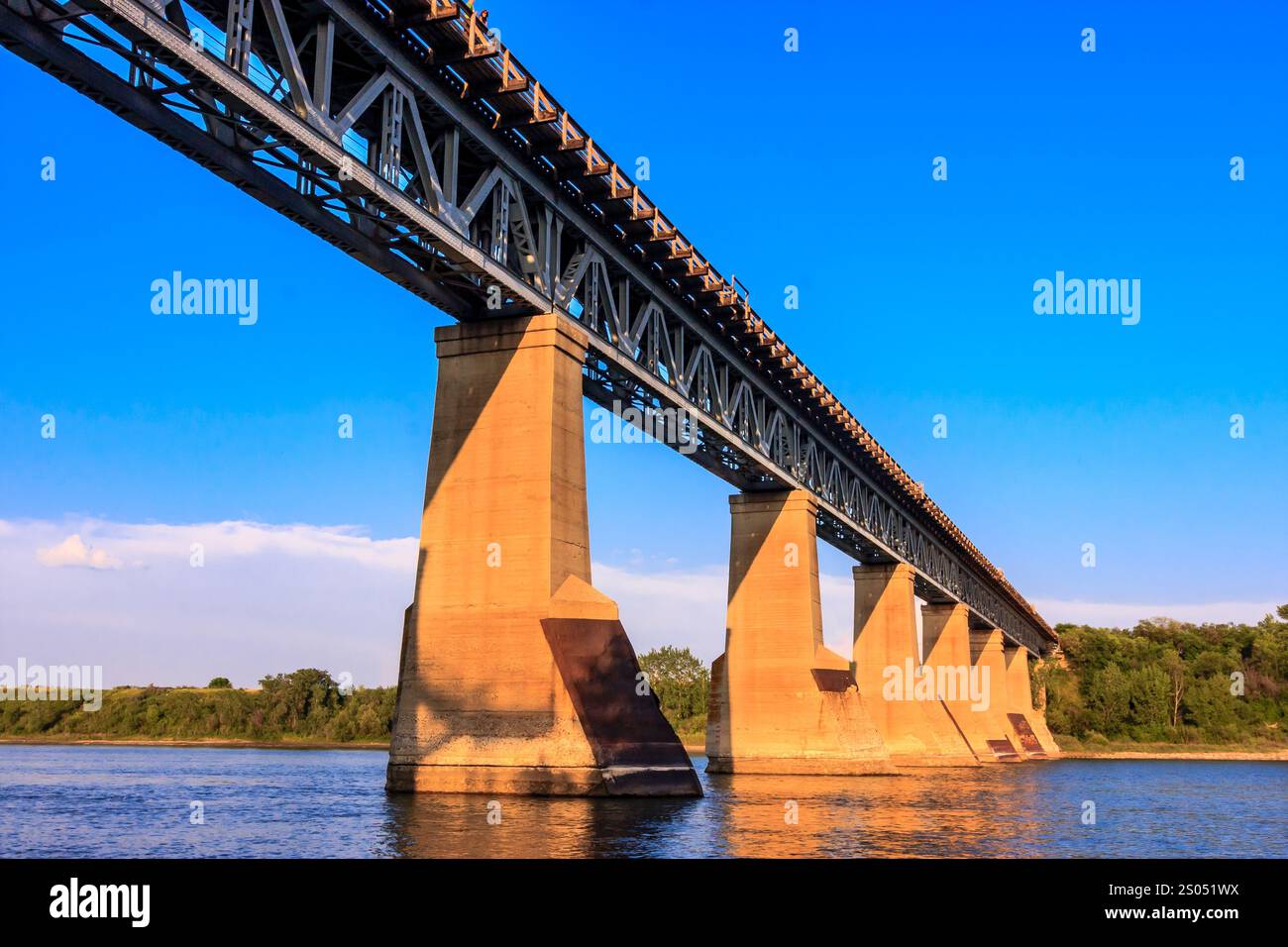 A bridge spans a river with a clear blue sky above. The bridge is made ...