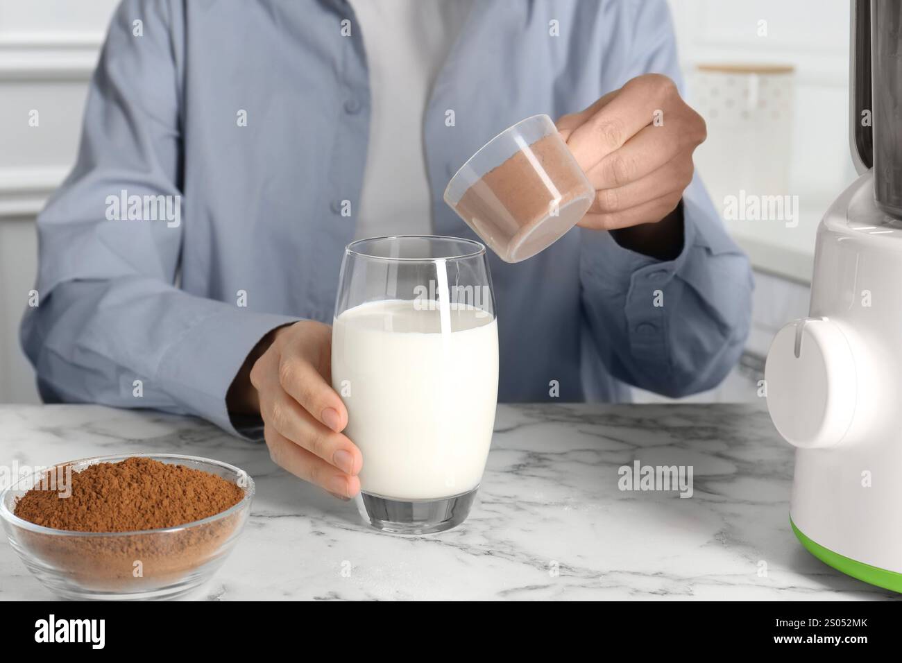 Making protein cocktail. Woman adding powder into glass with milk at ...