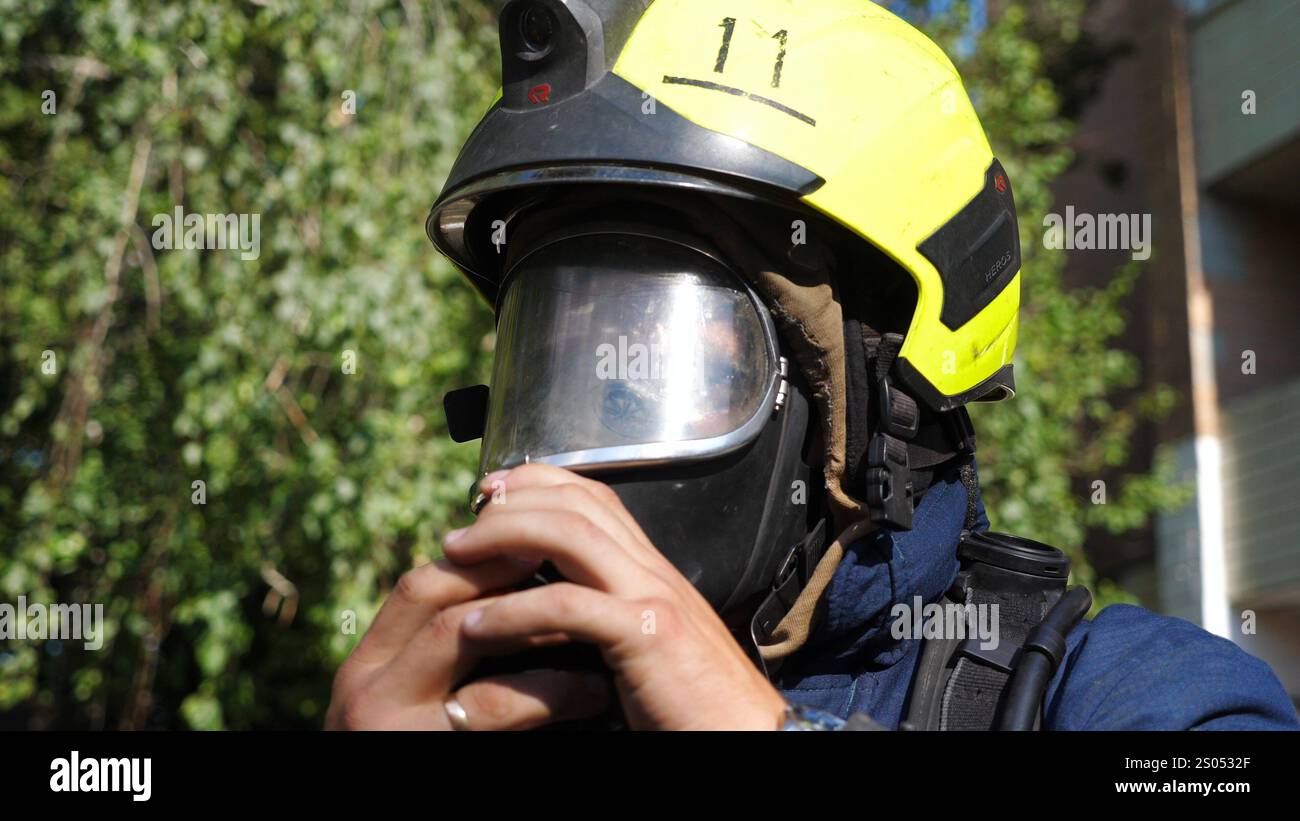 Young fireman connecting oxygen tank to the mask outdoor. Male ...