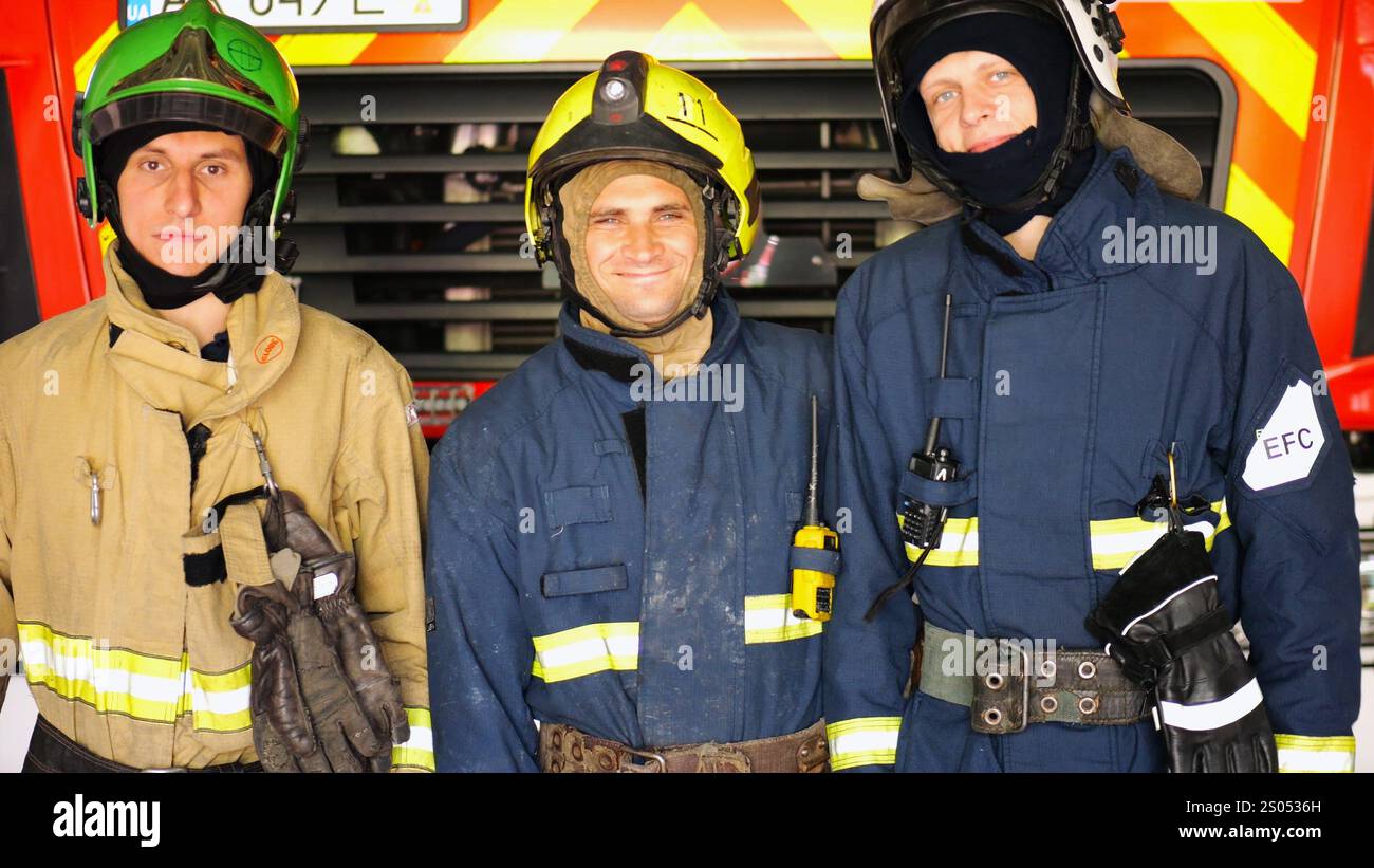 Portrait of young happy fireguards in protective uniforms against ...