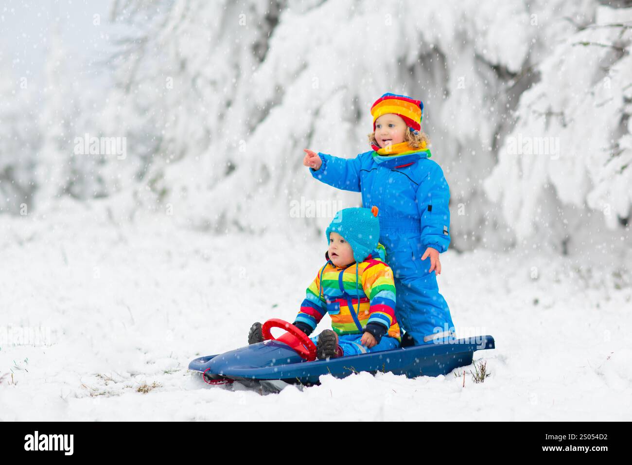 Kids play in snow in winter park. Children playing outdoors on snowy ...