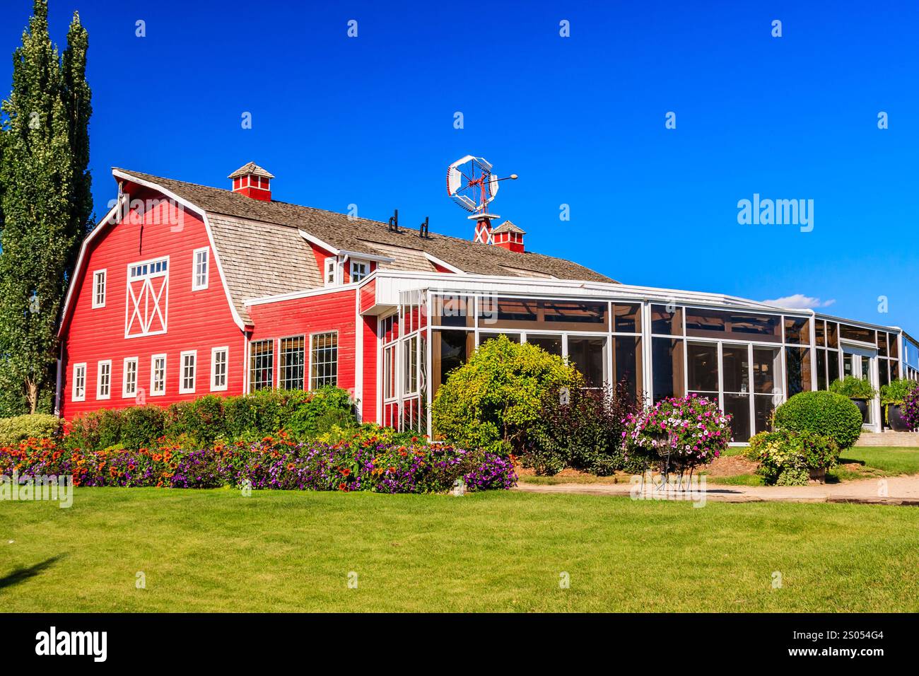 A red barn with a windmill on top and a white building with a glass ...