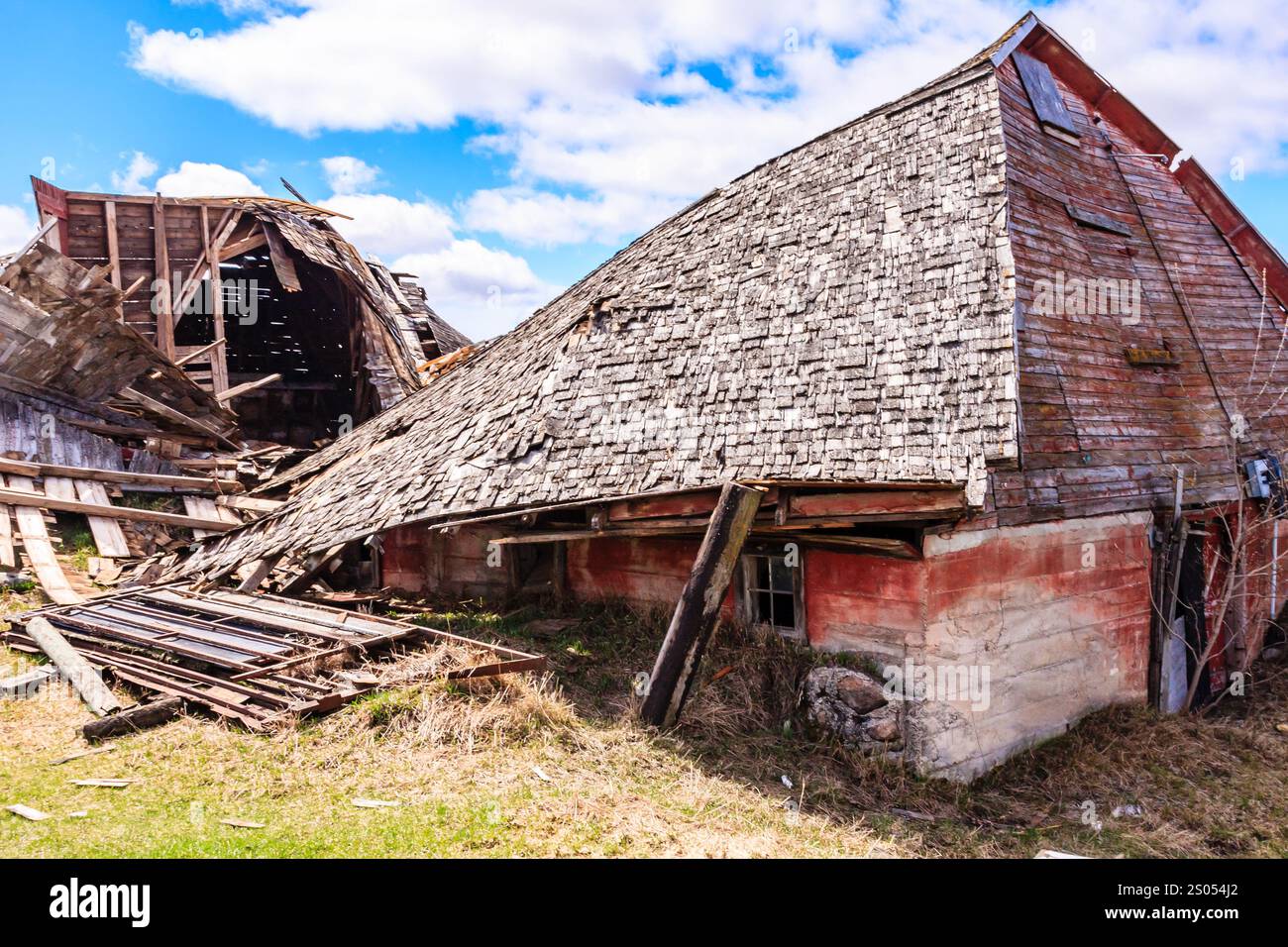 A barn with a roof that is falling apart. The barn is old and has a lot ...