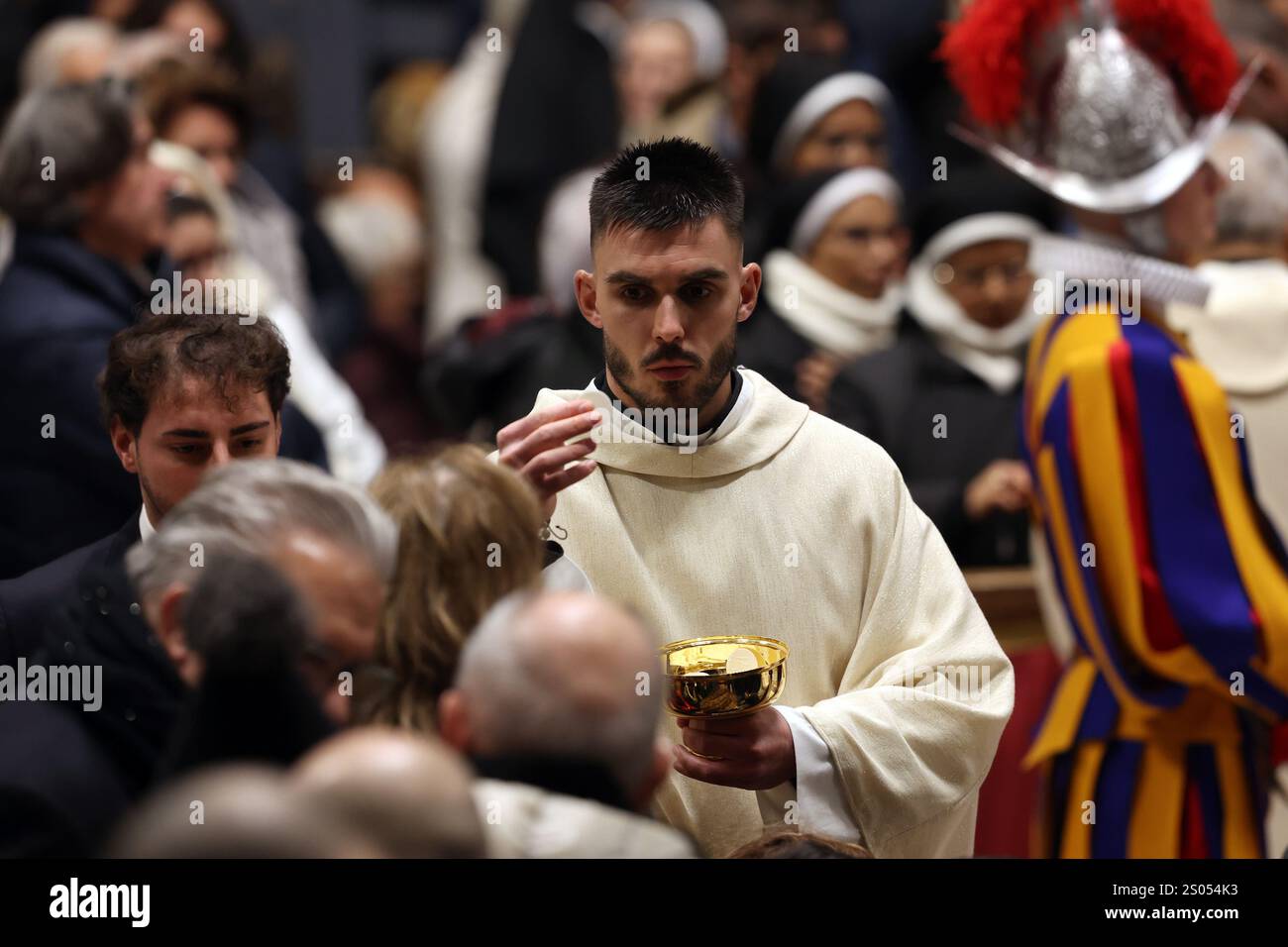 Vatican City, Italy 24.12.2024 : priest gives the host during the first ...