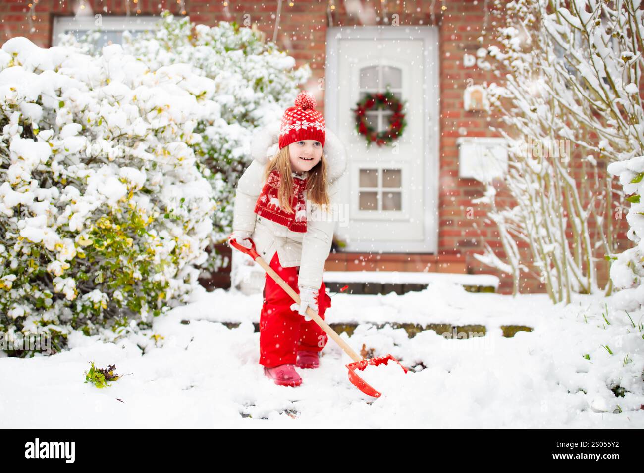 Child shoveling snow. Little girl with spade clearing driveway after ...