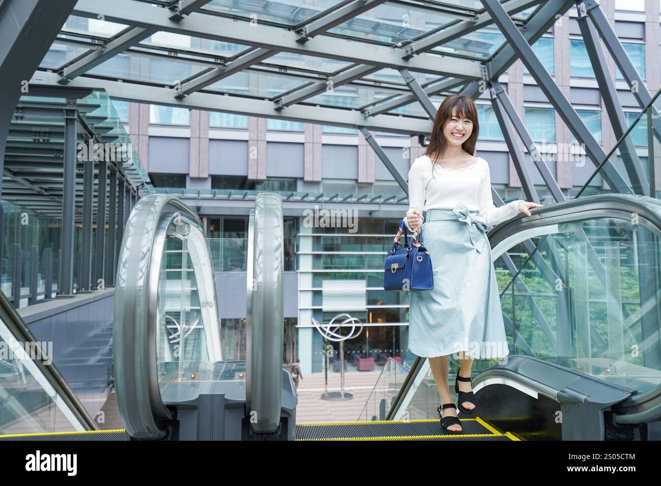 Woman riding escalator Stock Photo - Alamy