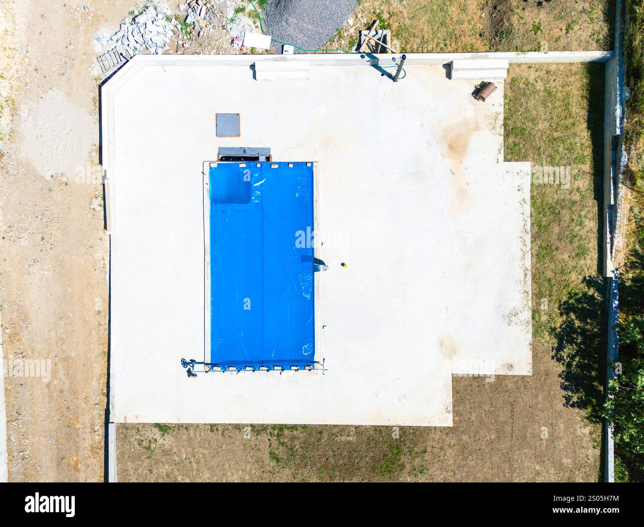 Aerial view of an unfinished backyard pool with a blue protective cover ...