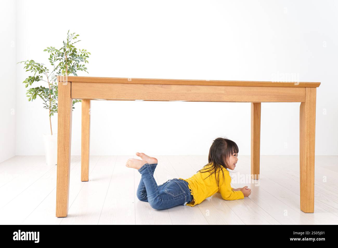 Child taking refuge under a desk Stock Photo - Alamy