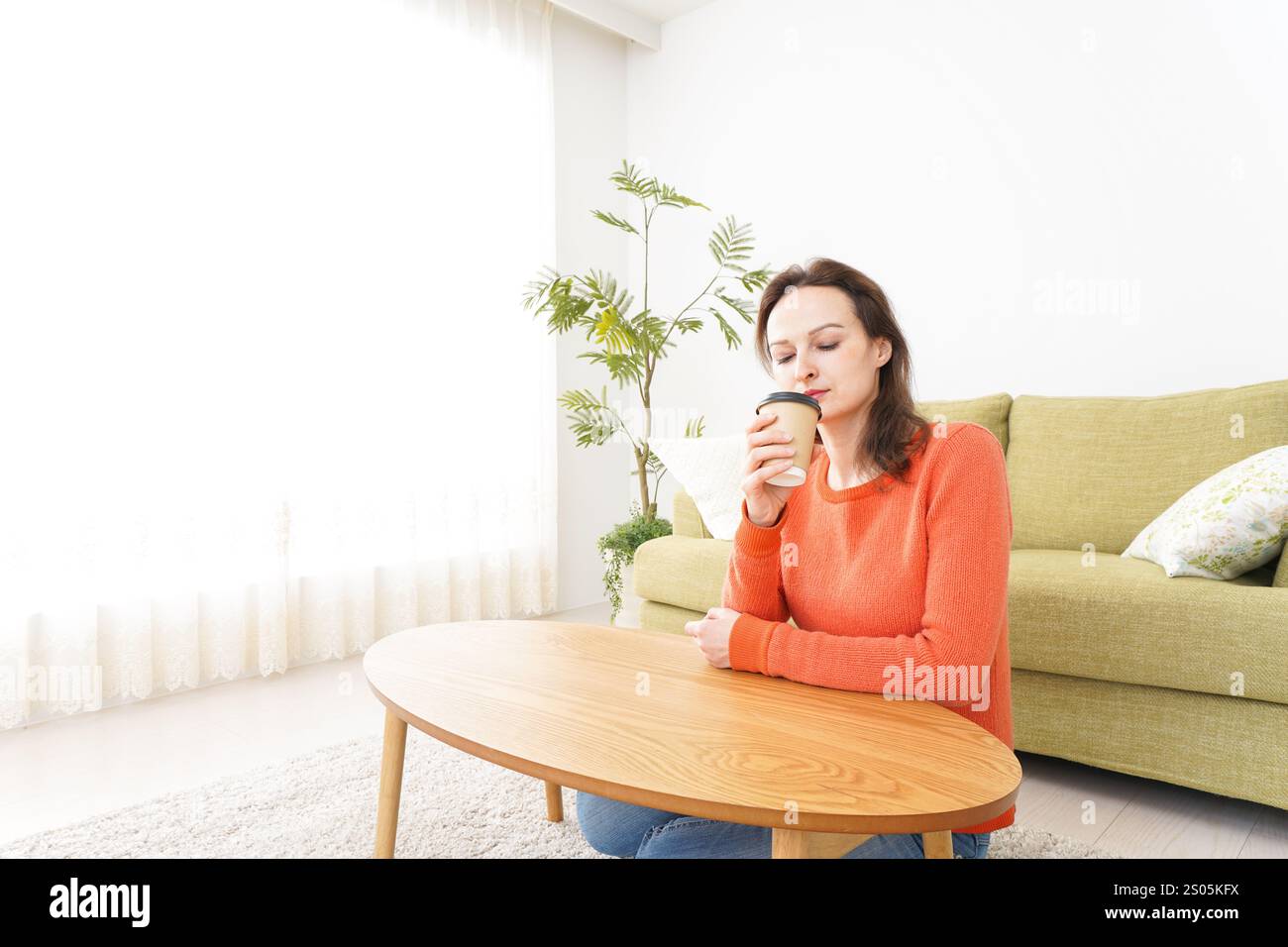 Young woman drinking coffee at home Stock Photo - Alamy