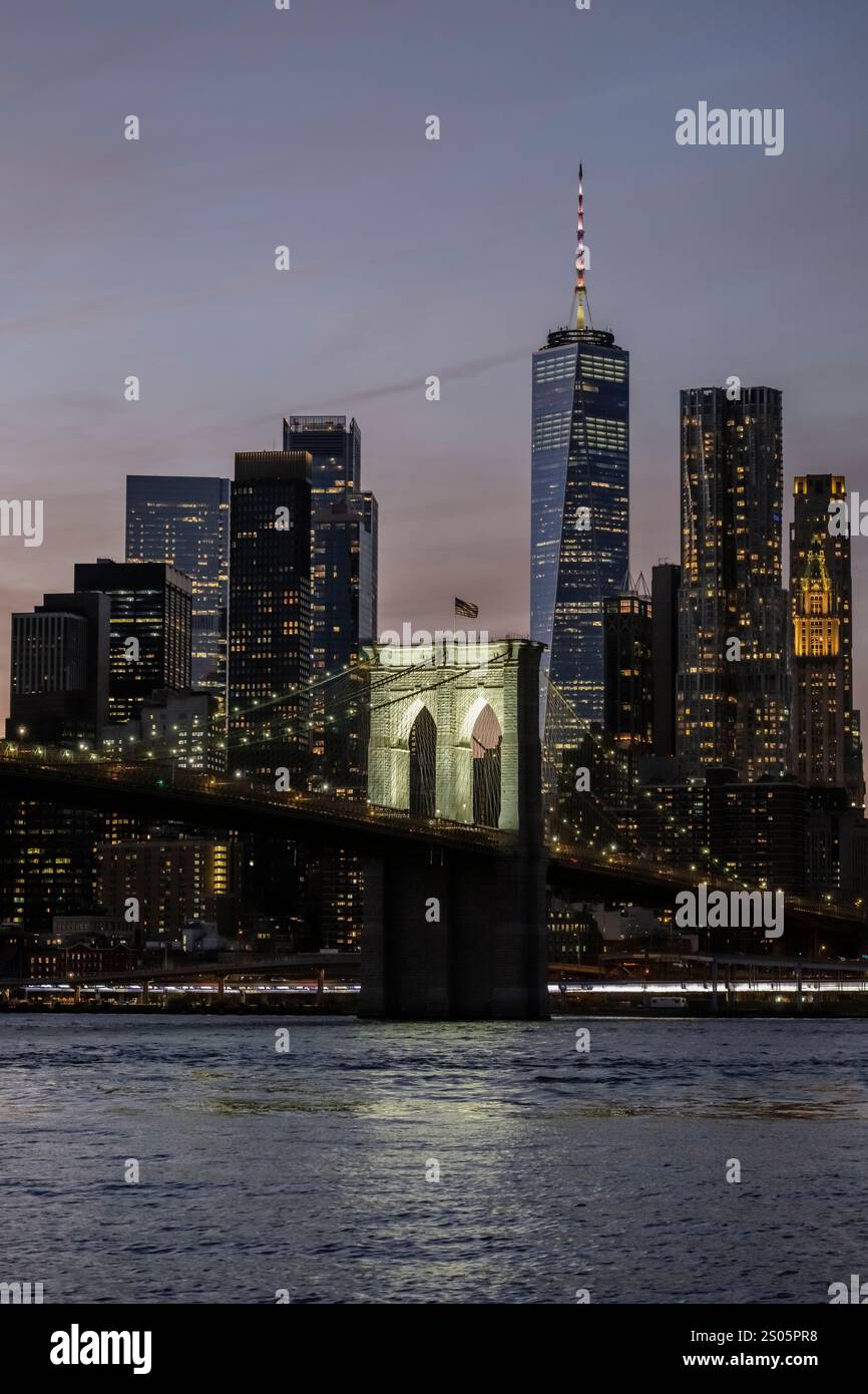 Illuminated Brooklyn Bridge stands against Manhattan's glowing skyline ...