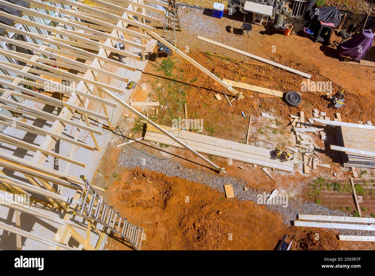 Workers are engaged in building framework structure with wooden beams while tools, materials are ...