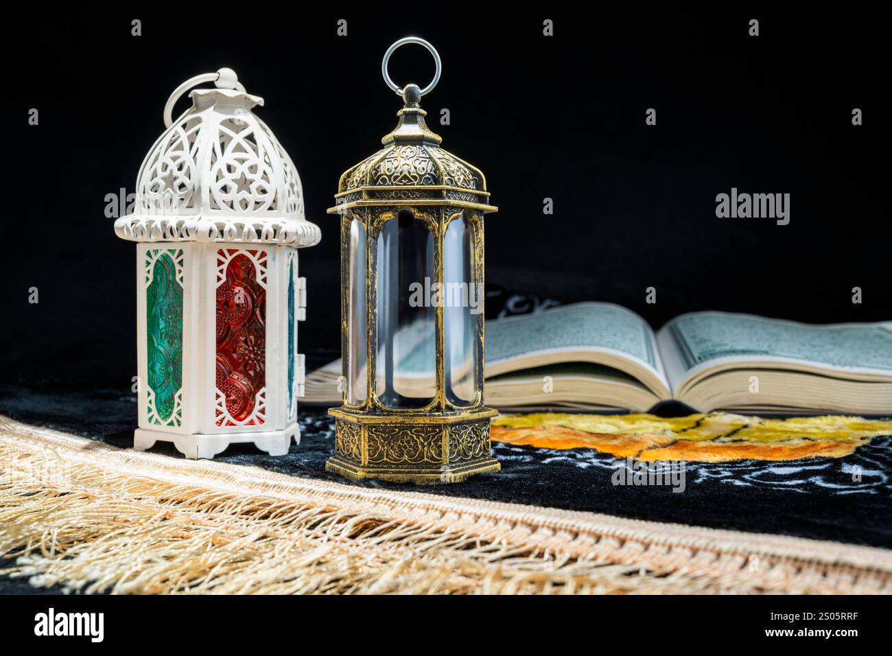 Arabic lanterns and Quran on a prayer mat with a black background ...