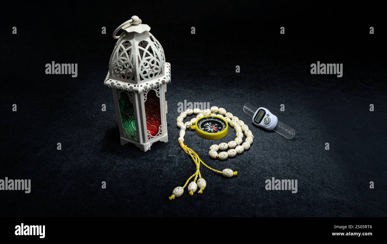 Arabic lantern with prayer beads and a qibla compass on a black ...