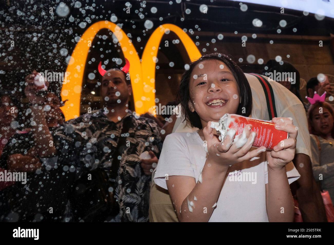 A little girl plays with snow spray during the Christmas eve ...