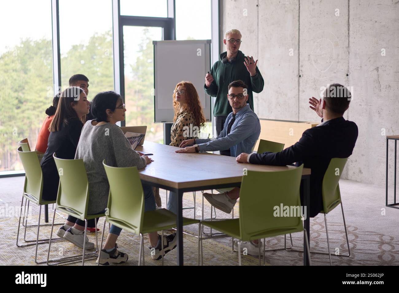 A young, diverse business team sitting together in a modern office ...