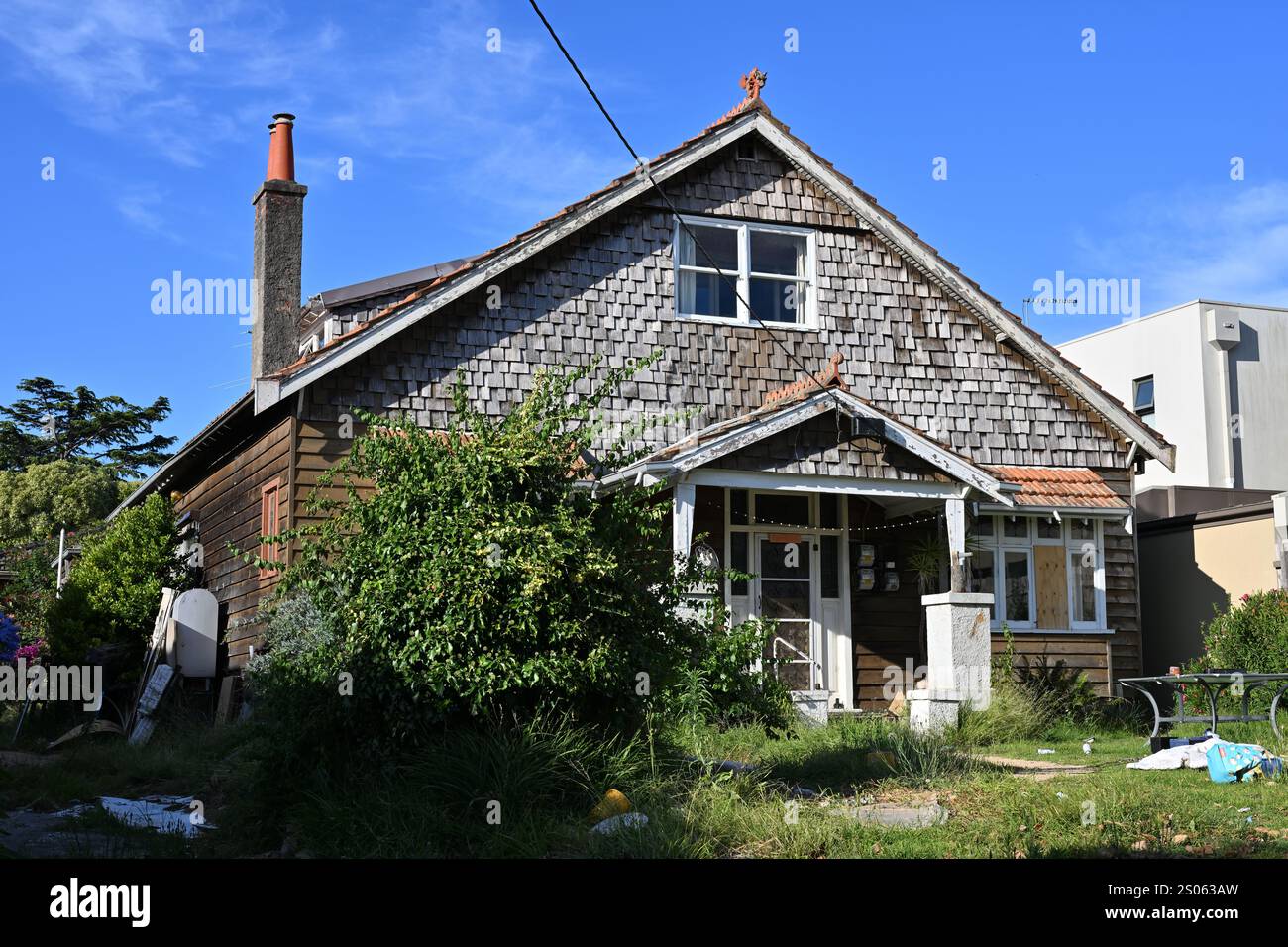 Exterior of an unkempt and decaying suburban home, with a messy yard ...