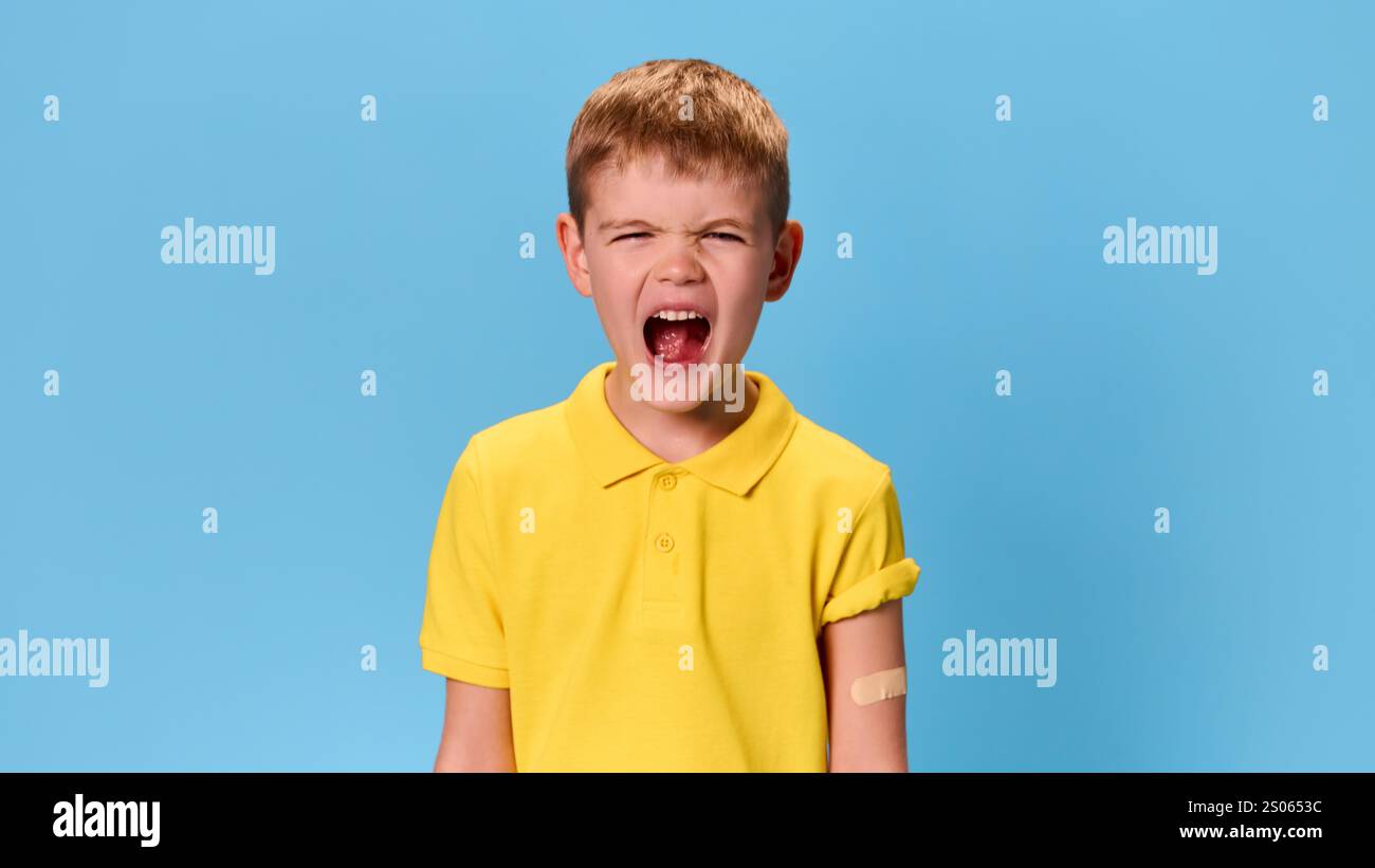 Boy in yellow shirt with bandage on hand, shouting energetically with ...
