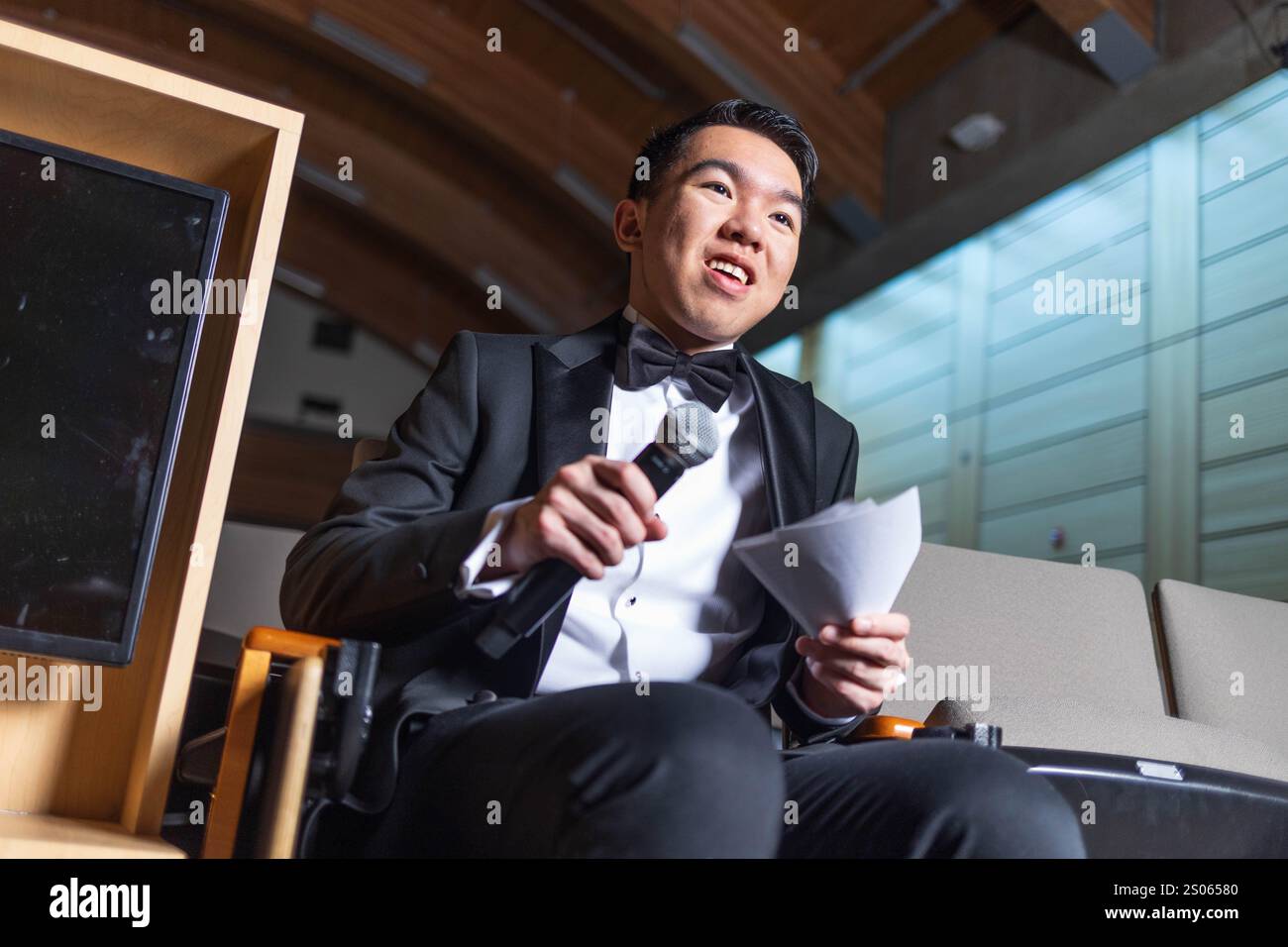 A young university student is at a public speaking competition, seated ...
