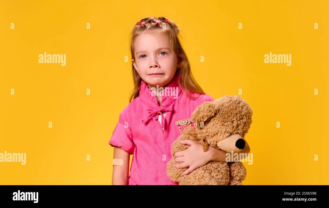 Girl in pink dress tearfully glancing sideways, clutching teddy bear ...