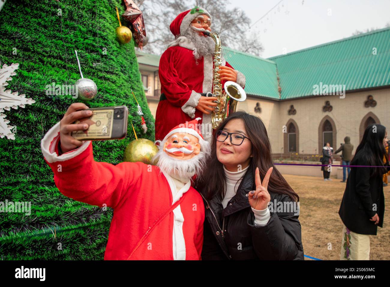 Srinagar, India. 25th Dec, 2024. A girl taking photos with Santa Claus ...