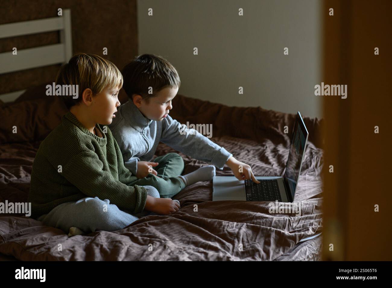 kids are sitting infront of the laptop on the bed for adaptive learning ...