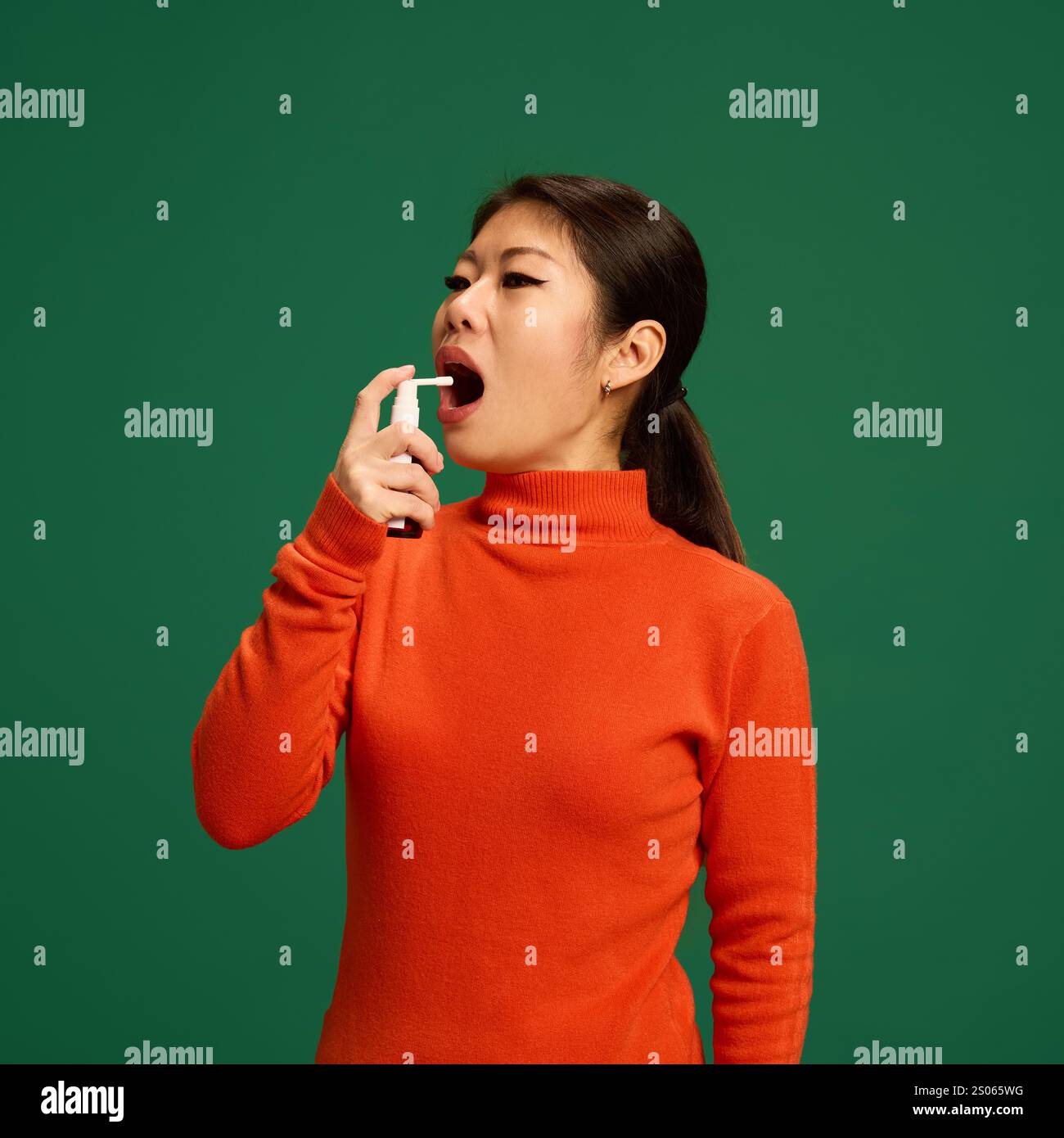 Woman using throat spray to ease pain and irritation caused by viruses ...