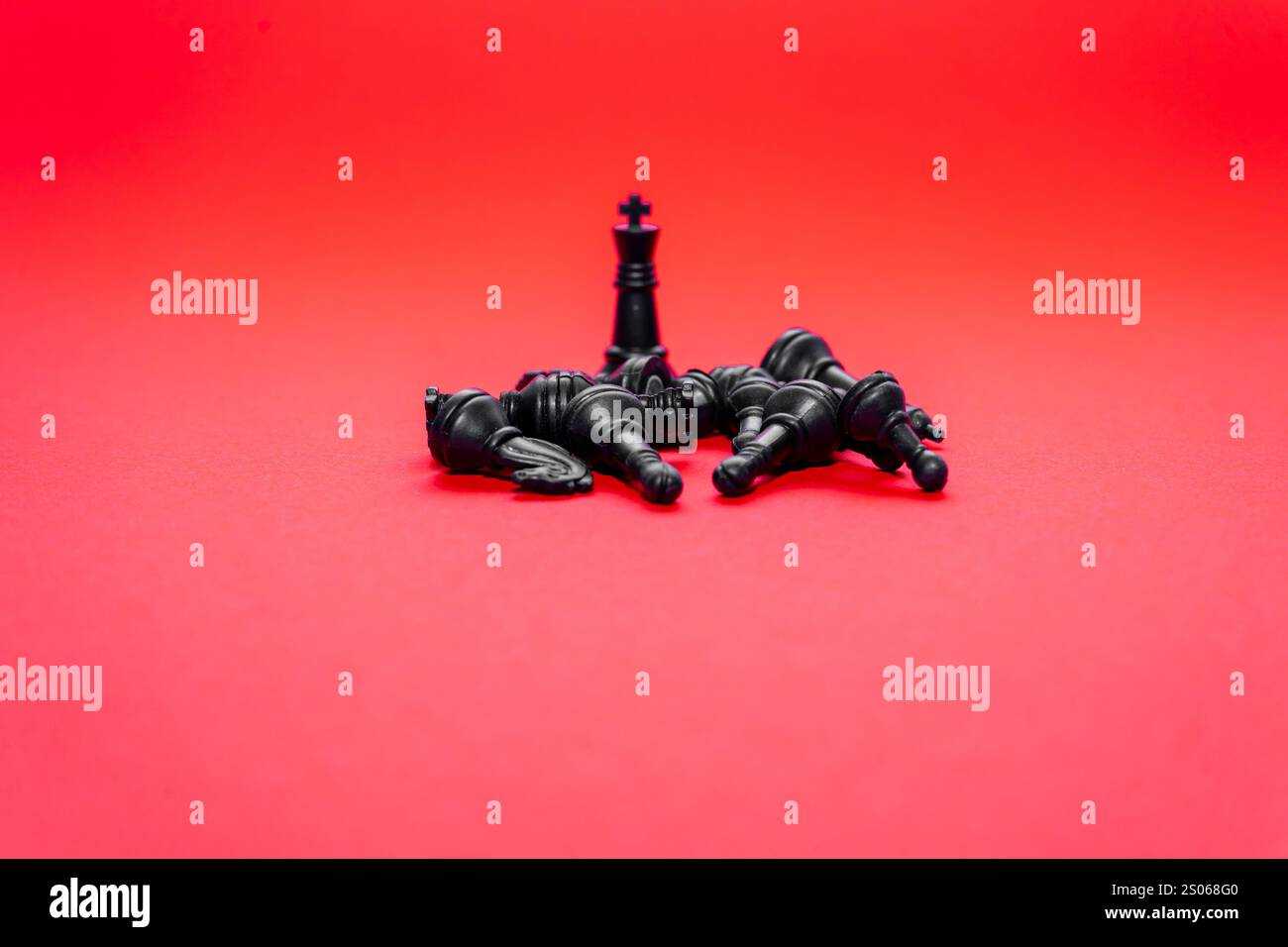 The black chess pieces lie on a bright red surface, signaling a ...