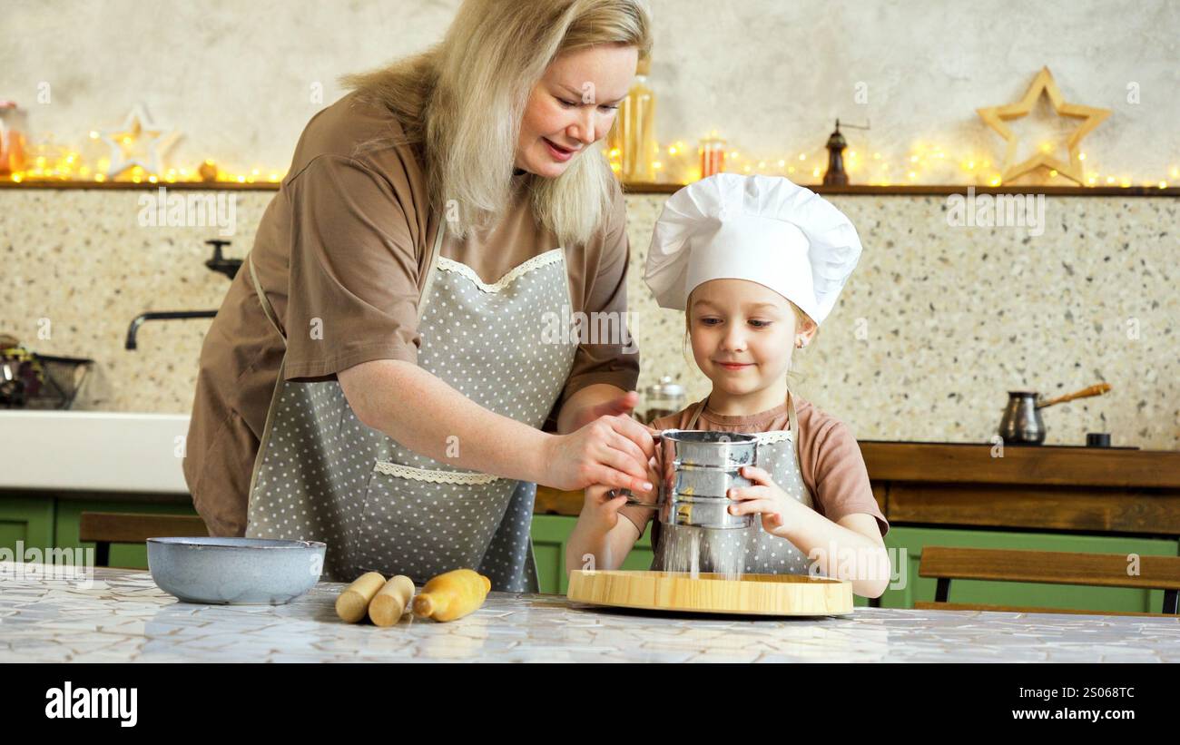 Teaching a child to sift flour in the kitchen Stock Photo - Alamy