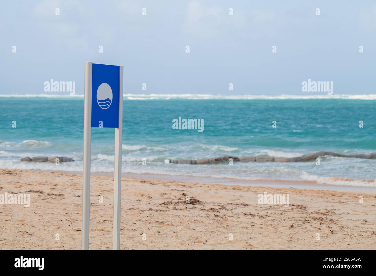 Coastal landscape with Blue Flag beach banner on white stand in the ...