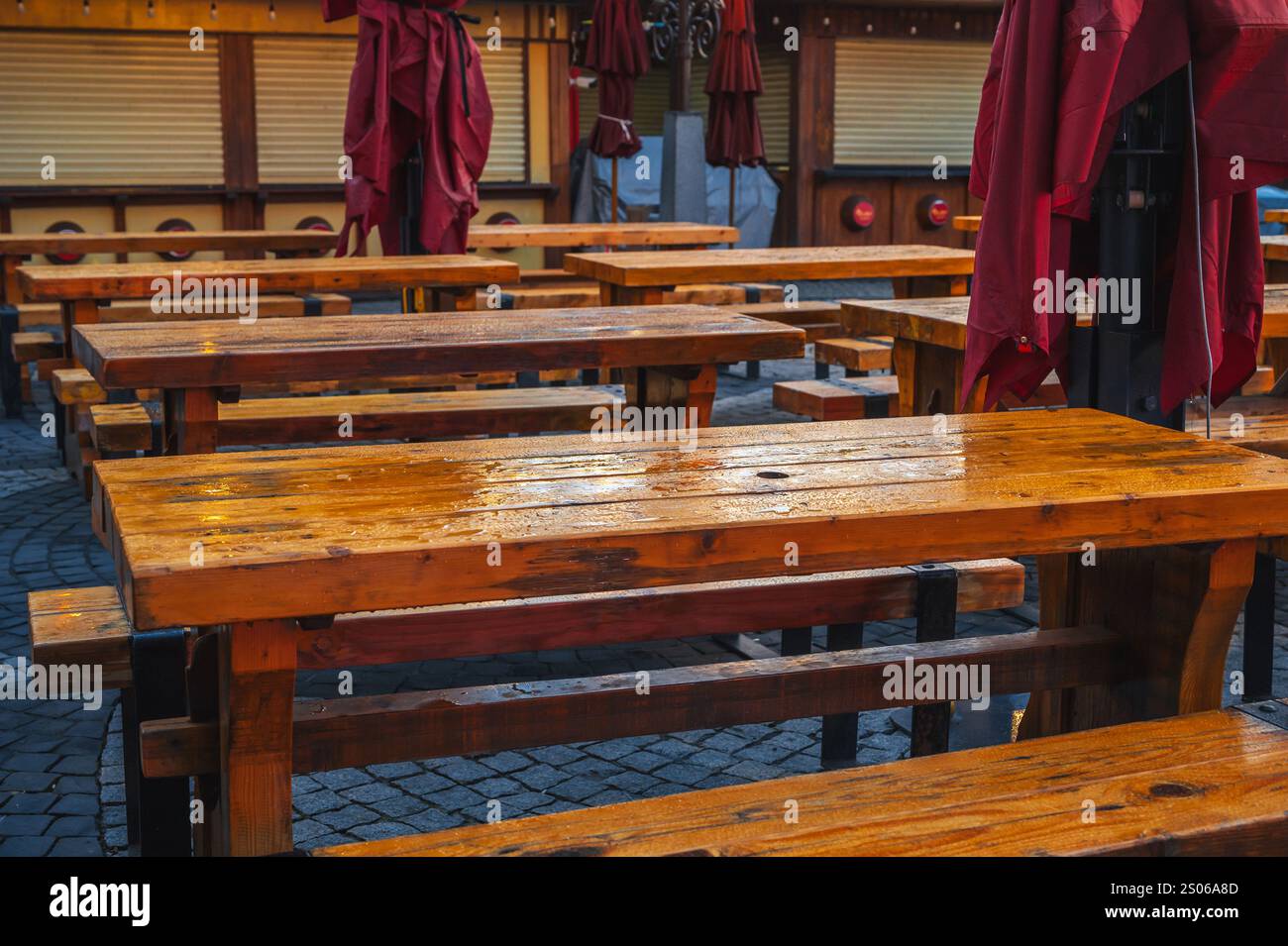 wet wooden tables and benches in a street cafe in Europe in the evening ...