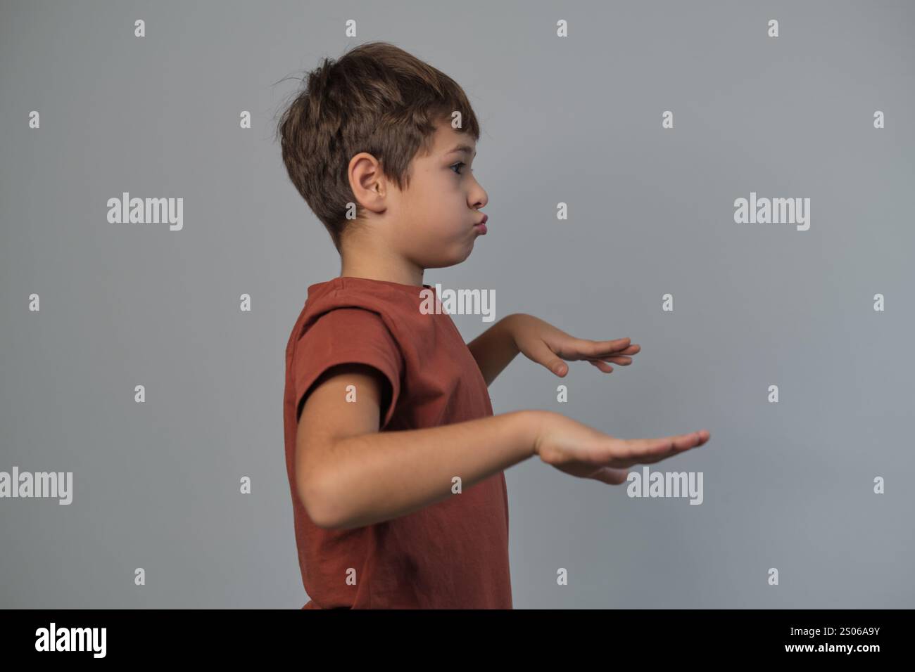 A child gestures playfully while making a humorous expression, captured ...