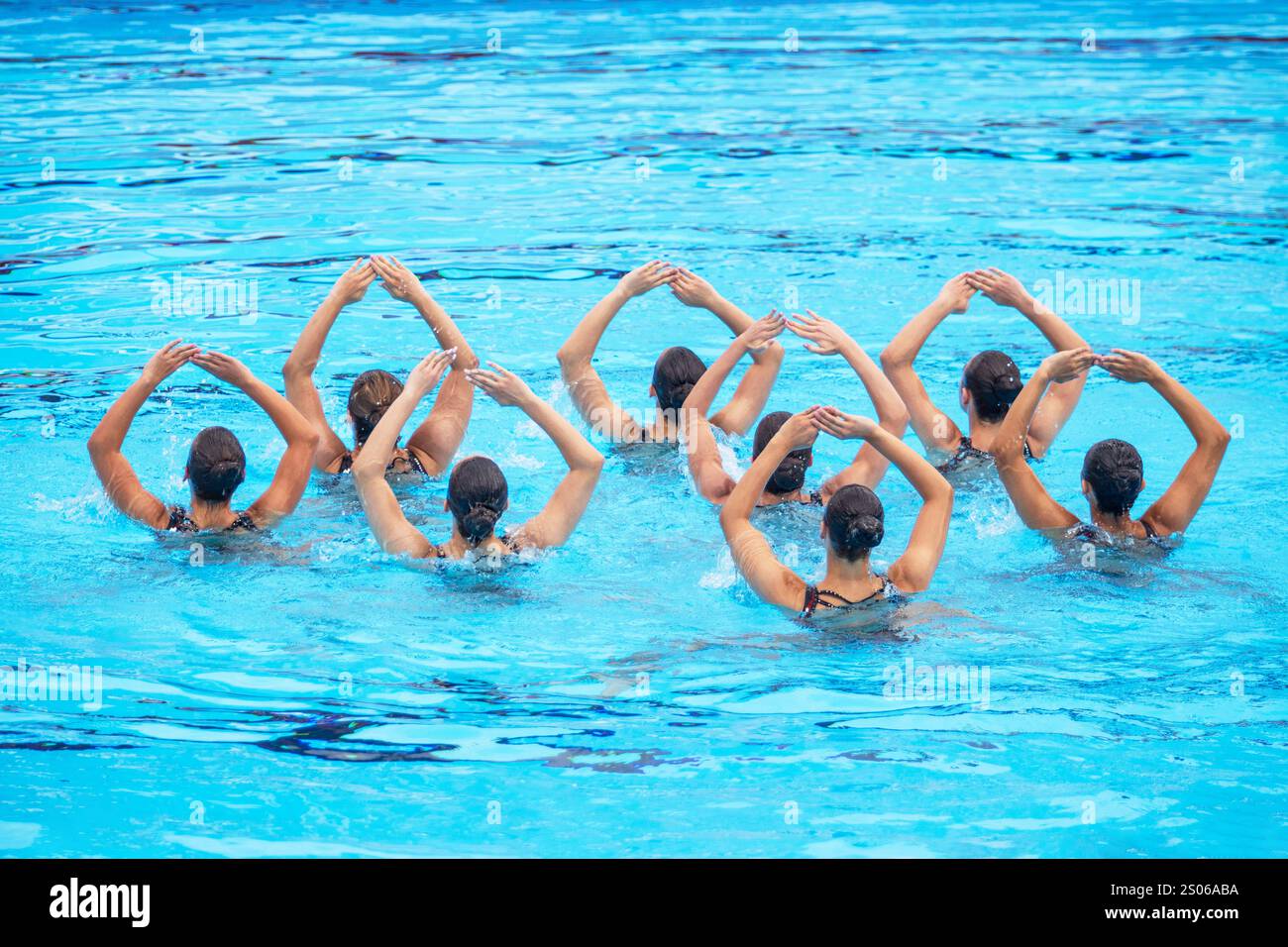 Artistic swimming team performing synchronized choreographed routine in ...
