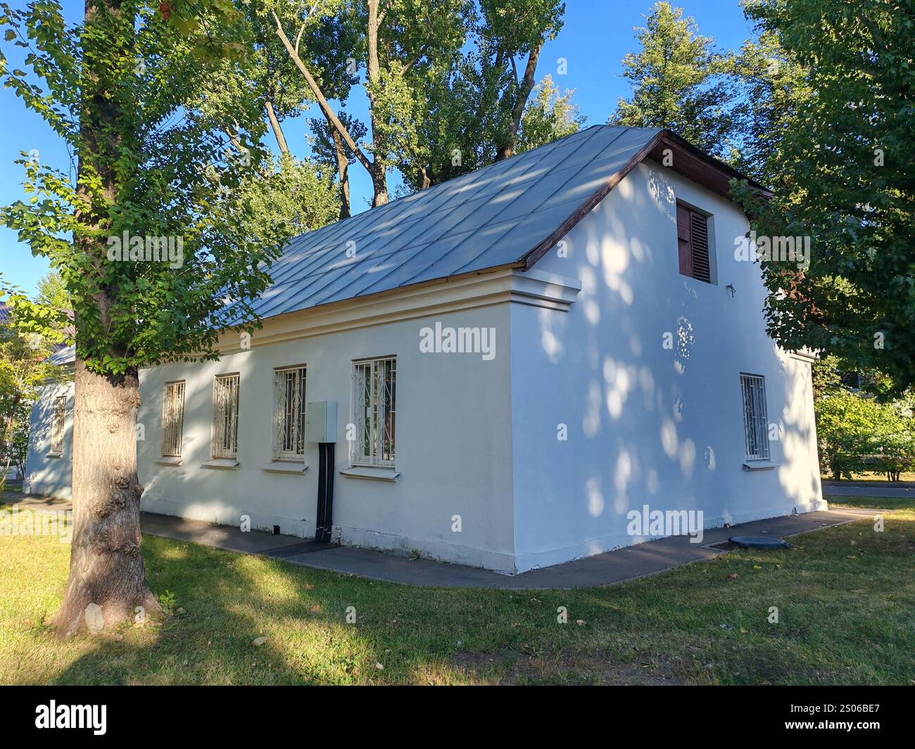 modest house with a metal roof and white facade, surrounded by lush ...