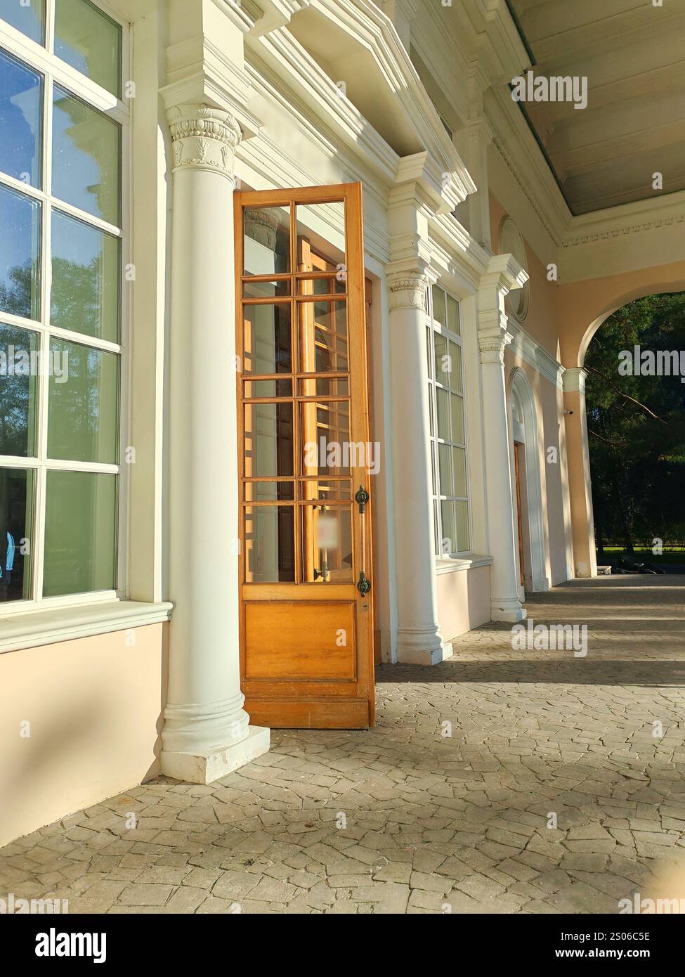 A neoclassical building with tall white columns and an open wooden door ...
