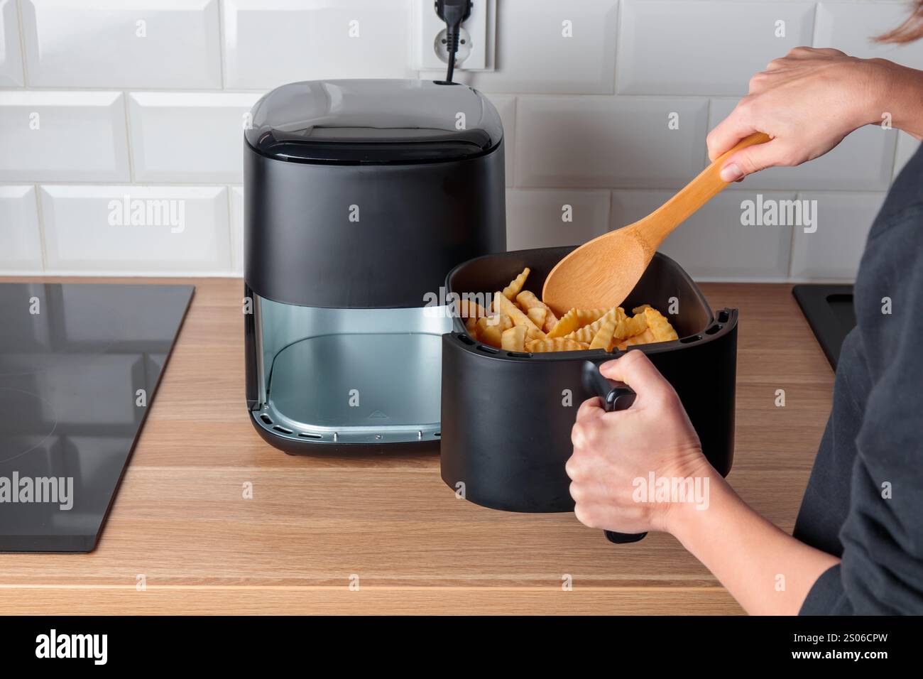 Woman at home using trendy kitchen gadget air fryer machine cooking ...