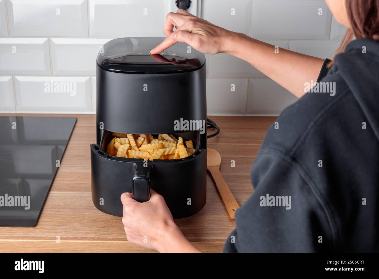 Woman at home using trendy kitchen gadget, deep fryer, selecting ...