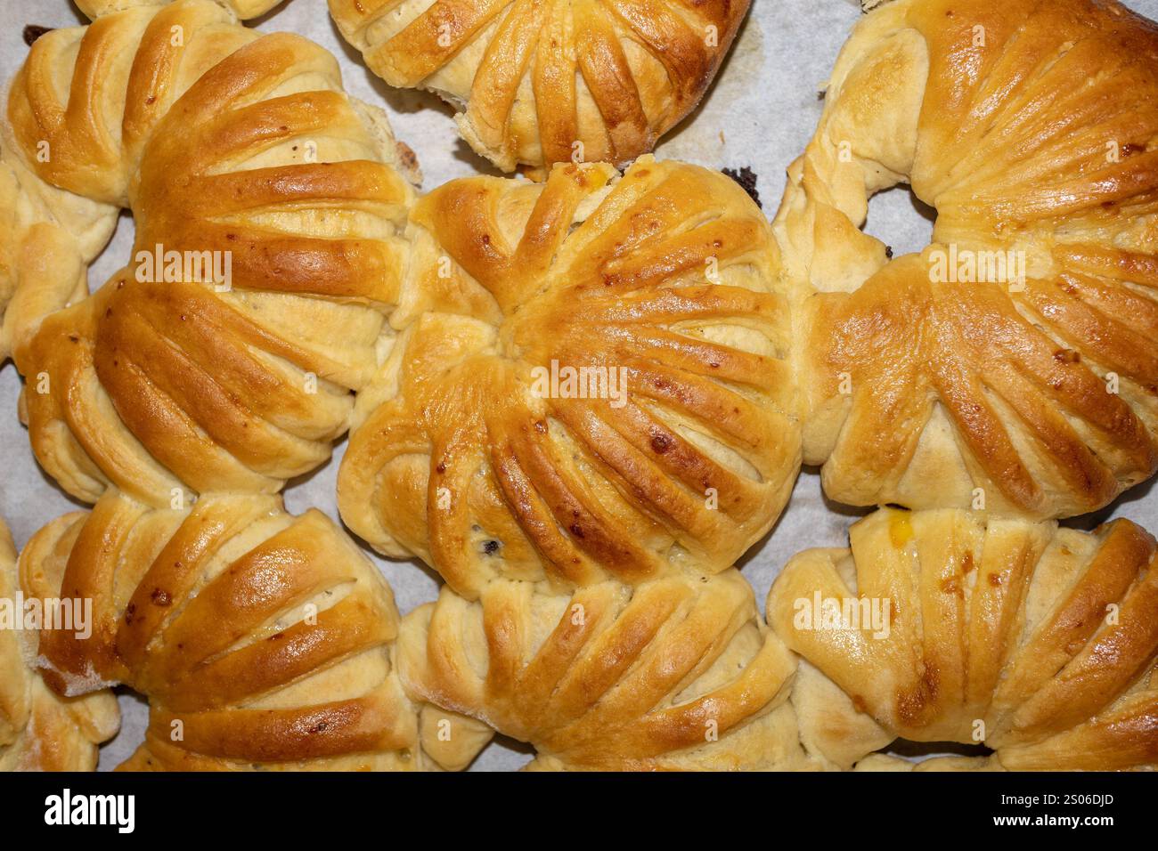 Golden brown pastries with intricate slits, freshly baked and laid out ...