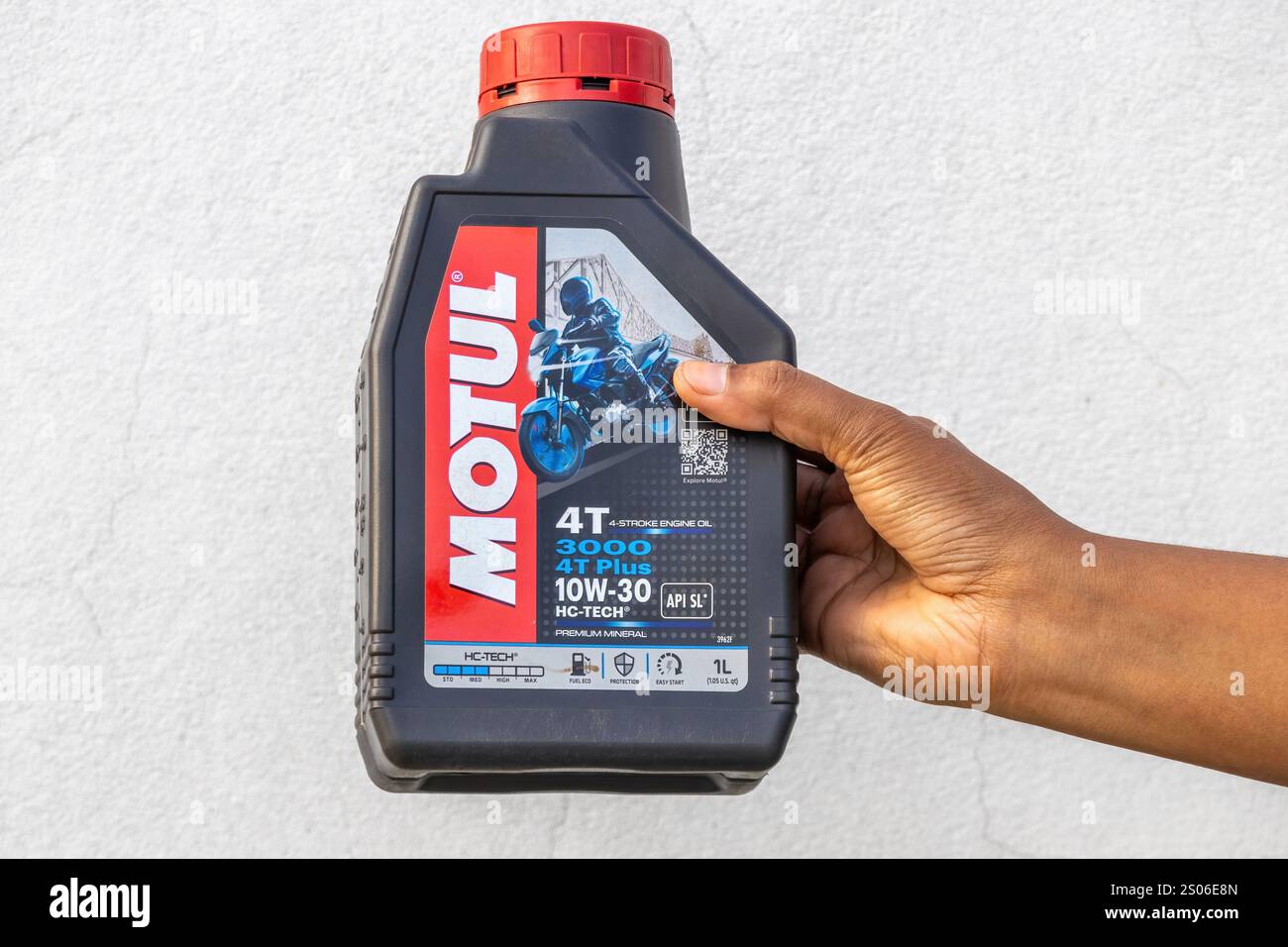 A woman's hand holding a bottle of Motul 3000 4T Plus 10W-30 Premium ...