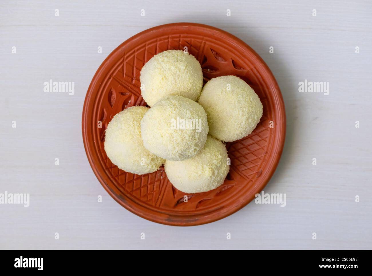 Tasty Kachagolla sweets served on a clay plate on a wooden background ...