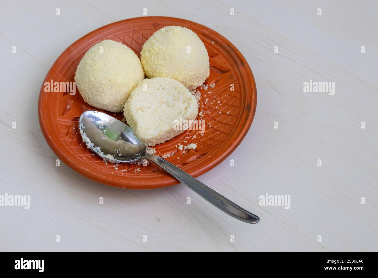 Tasty Kachagolla sweets and a spoon, served on a clay plate, rest on a ...