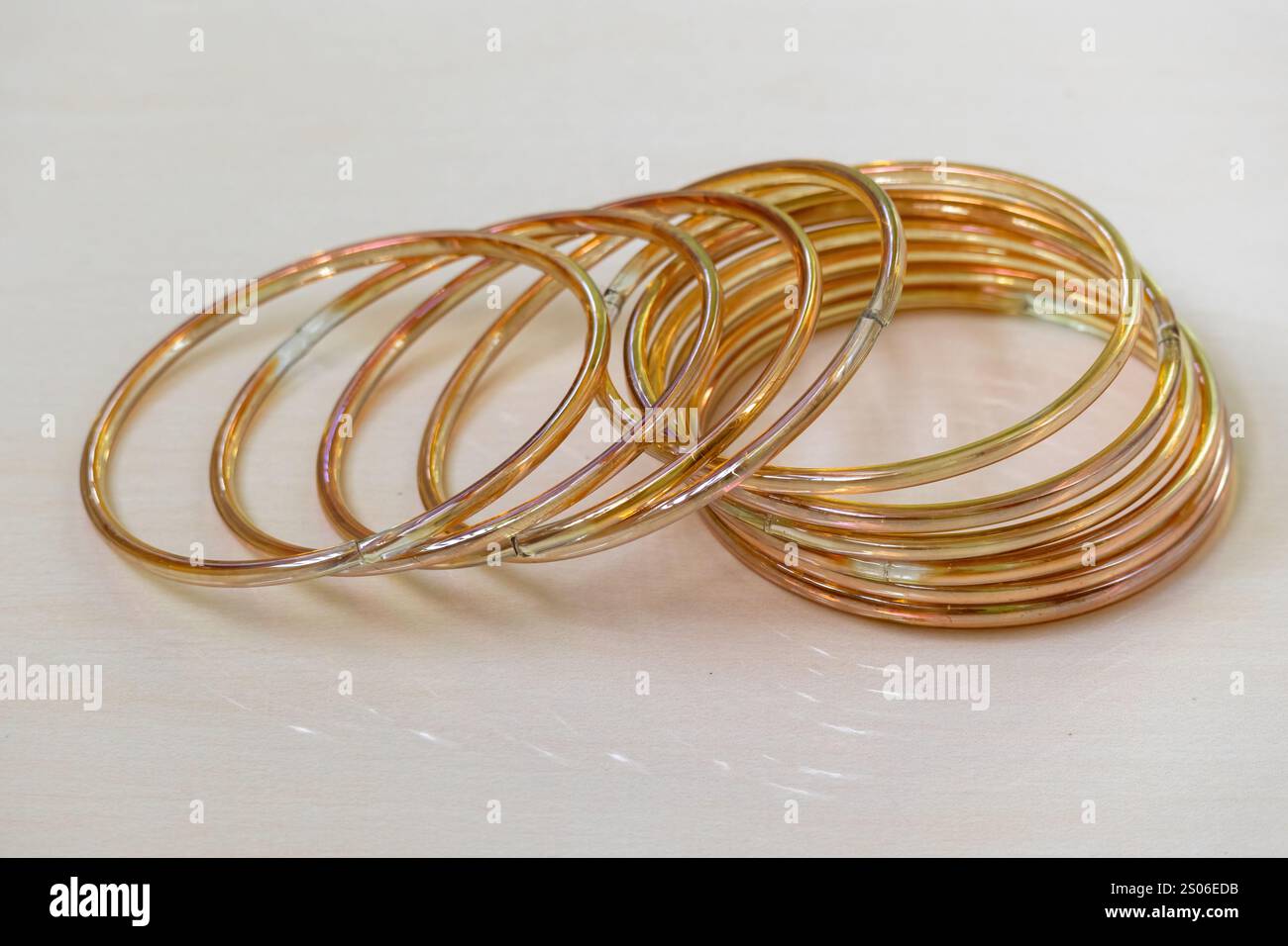 Golden glass bangles, isolated on a wooden tile background. Churi or ...