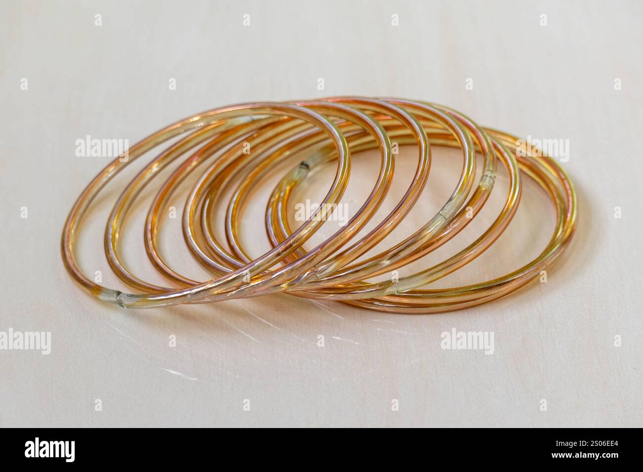 Golden glass bangles, displayed on a wooden tile background. Churi or ...