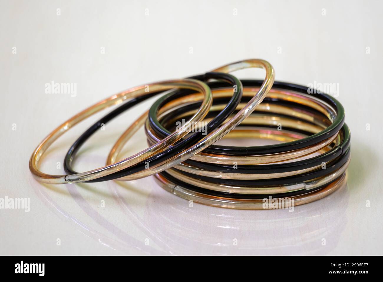 Elegant black and gold glass bangles, displayed on a wooden tile ...