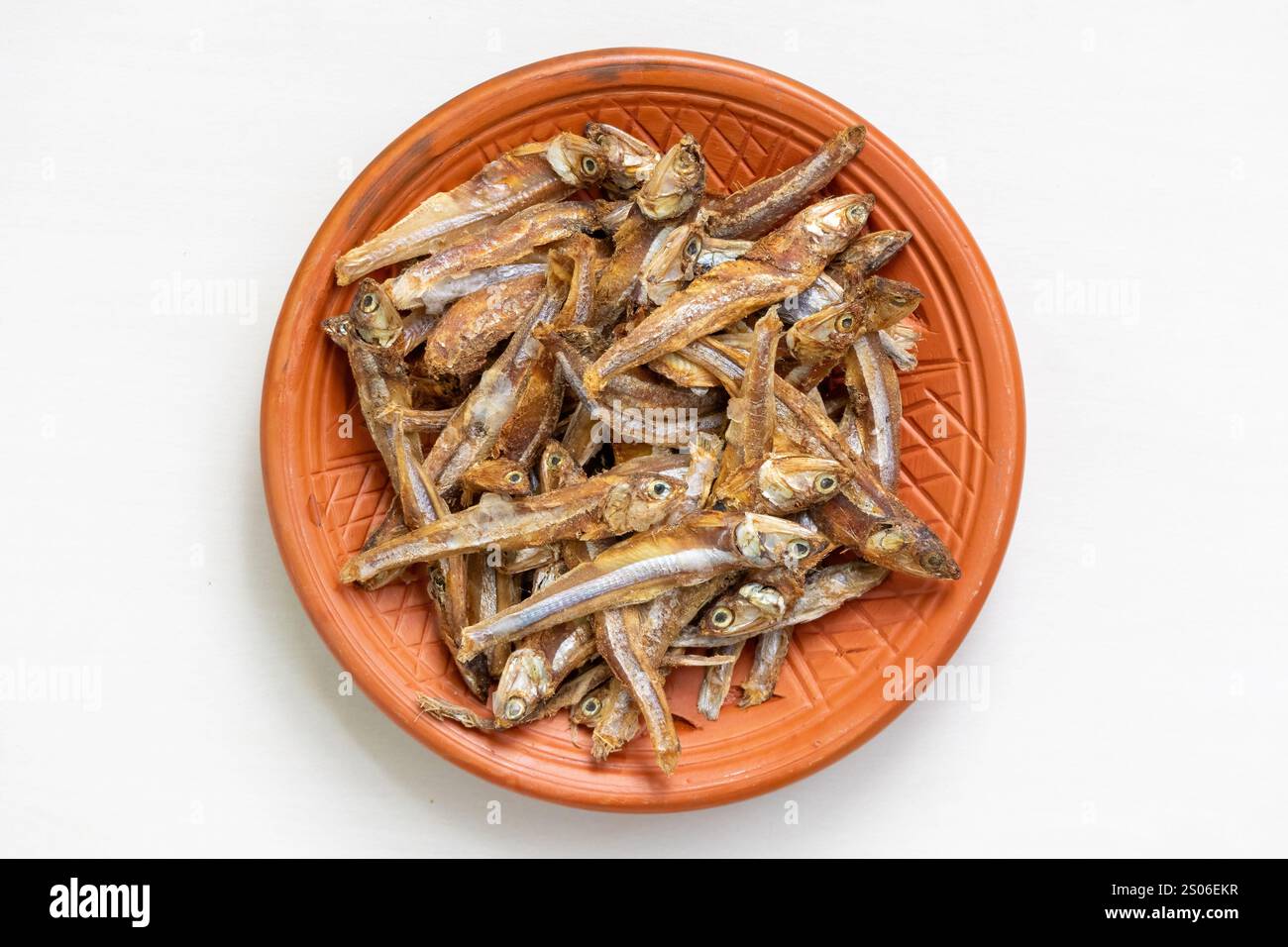 Dried anchovy fish, known as Mola Shutki in Bangladesh, on a clay plate ...